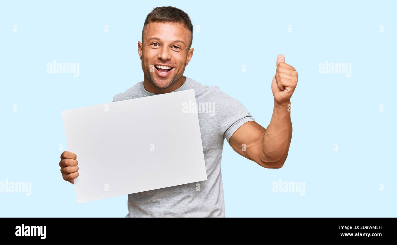 Handsome muscle man holding blank empty banner screaming proud ...