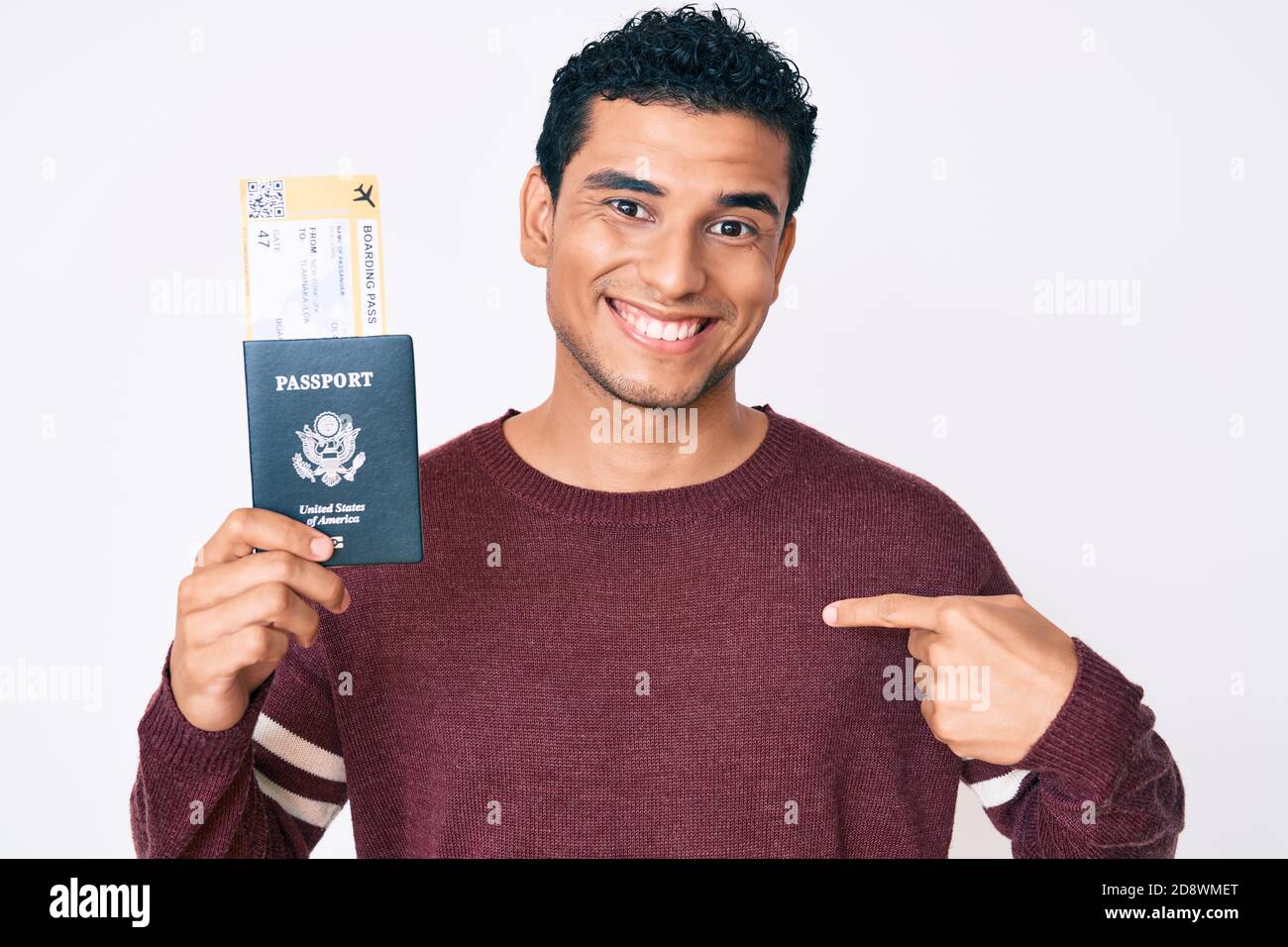 Young handsome hispanic man holding boarding pass and passport pointing ...