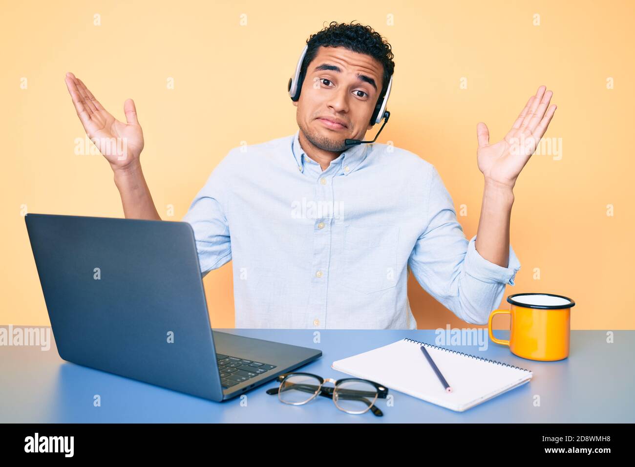 Young handsome hispanic man working at the office wearing operator ...