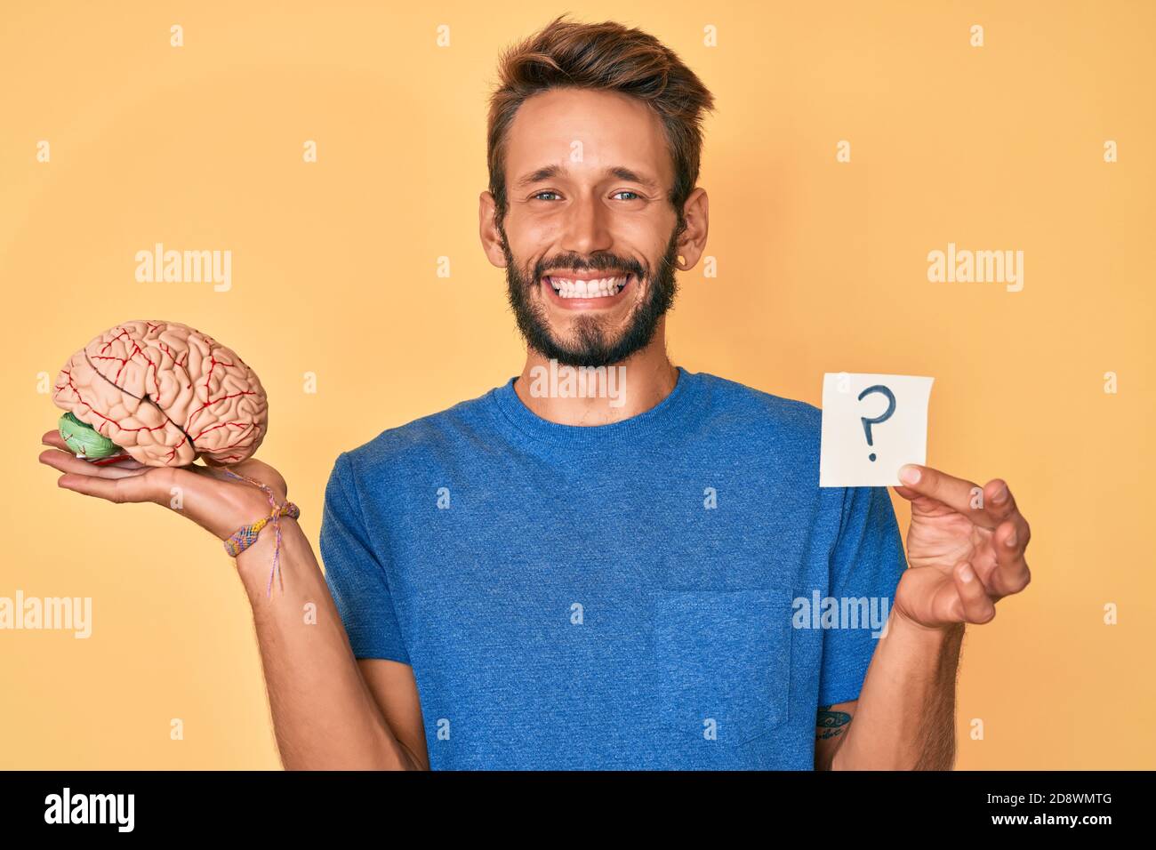 Handsome caucasian man with beard holding brain and question mark ...