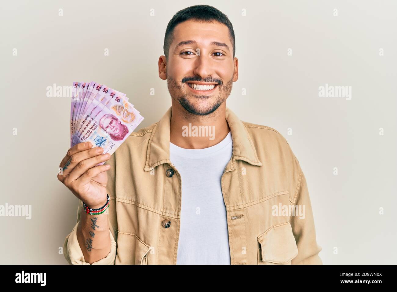 Handsome man with tattoos holding 50 mexican pesos banknotes looking ...