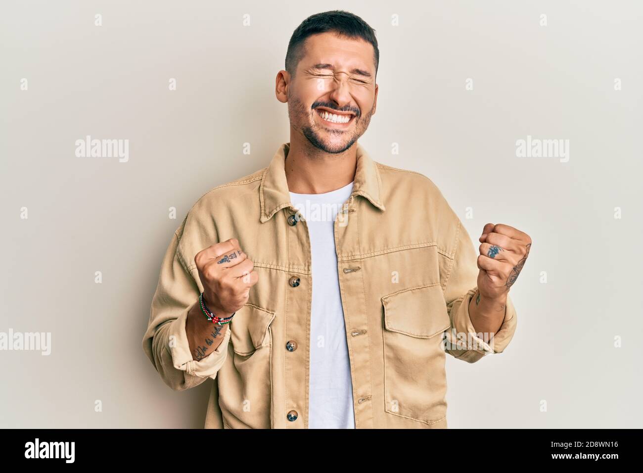 Handsome man with tattoos wearing casual brown denim jacket excited for ...