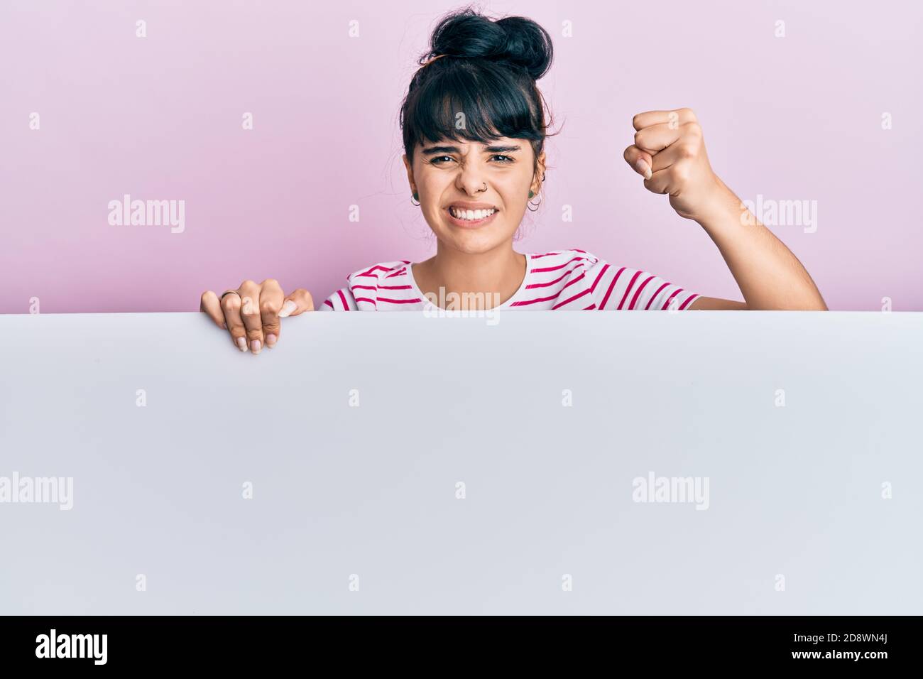 Young hispanic girl holding blank empty banner annoyed and frustrated ...