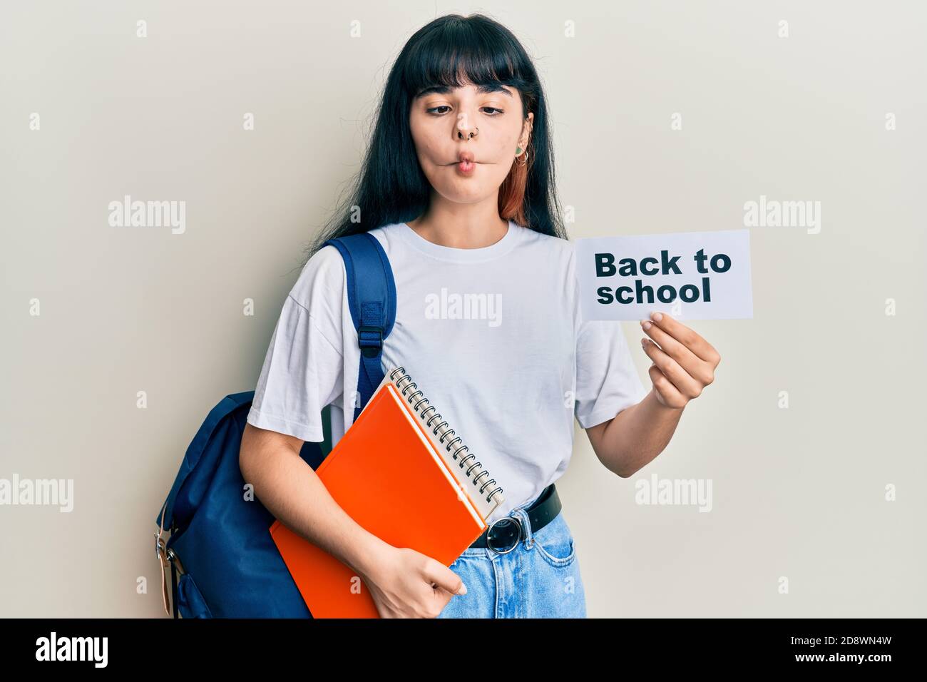 Young hispanic girl wearing backpack holding back to school banner ...