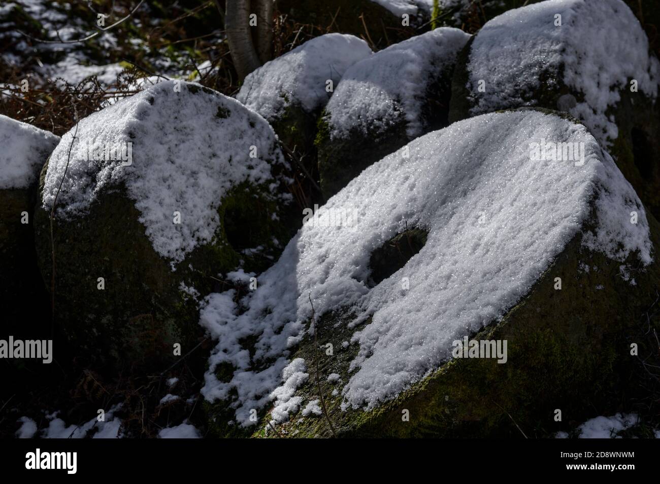 Abandoned carved and chiselled, round mill stones lit by moonlight ...