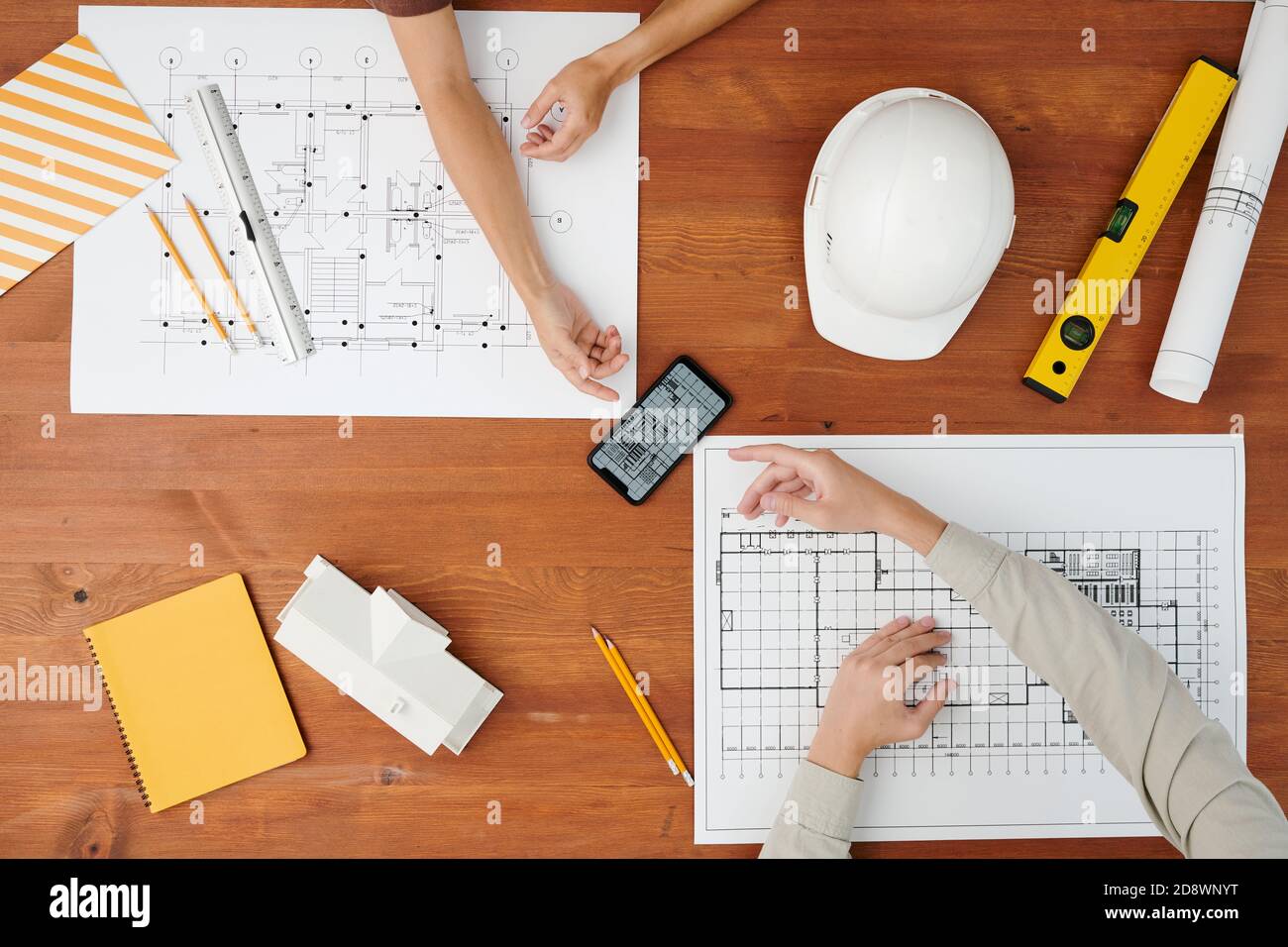 Above view of hands of creative architects pointing at smartphone with ...