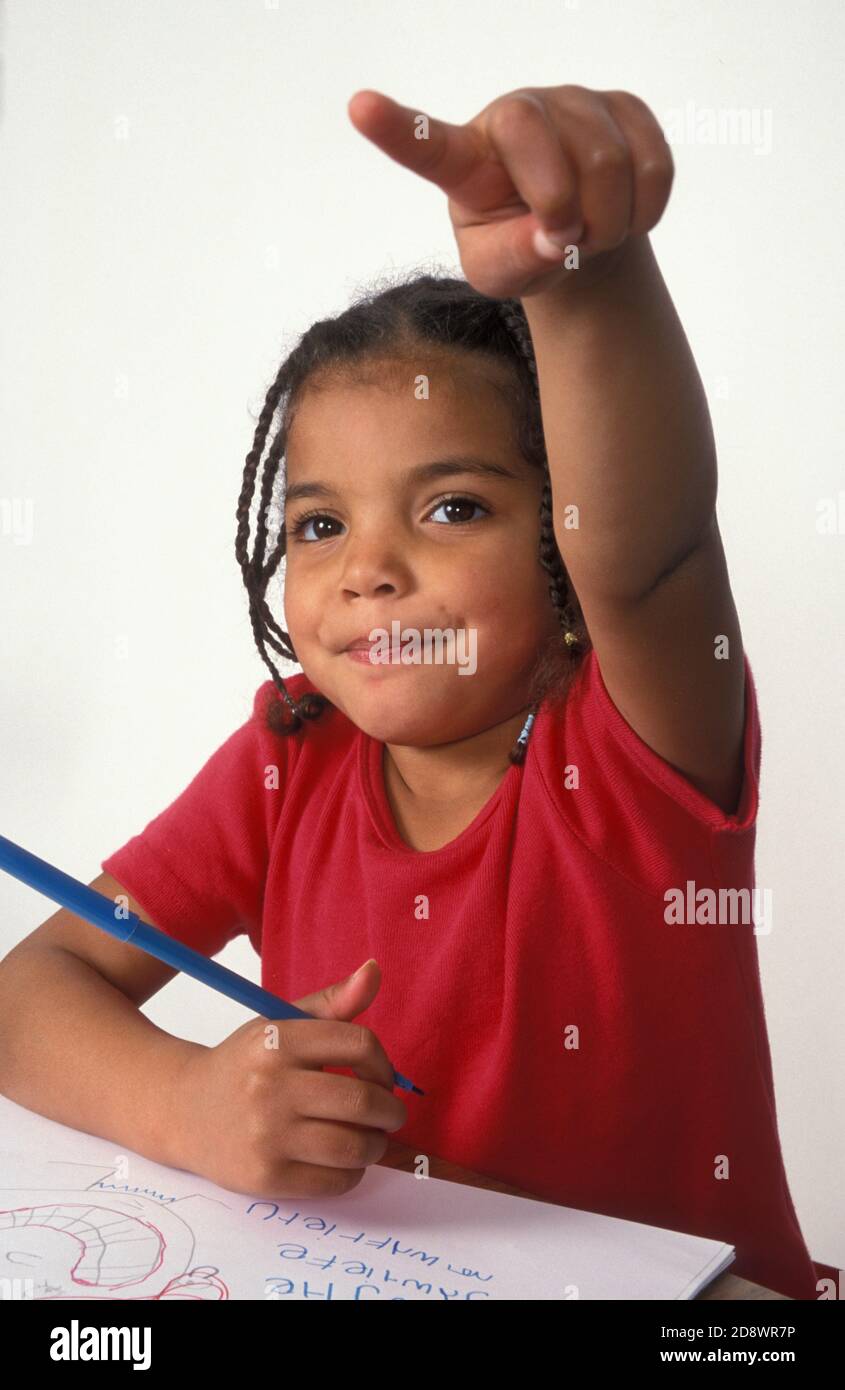 little girl putting hand up in classroom Stock Photo - Alamy