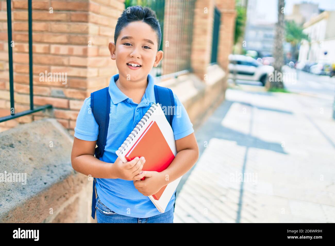 Adorable student boy smiling happy holding book at street of city Stock ...