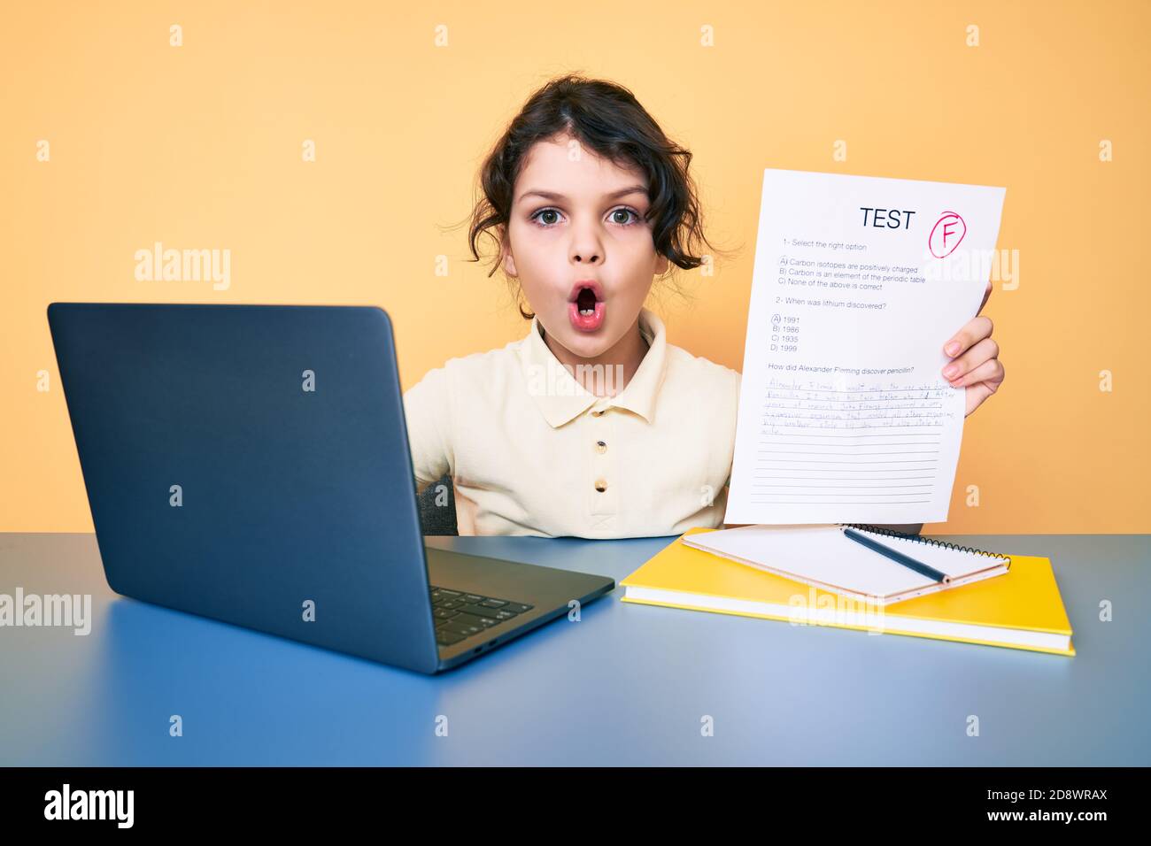 Cute hispanic child showing failed exam sitting on the desk scared and ...