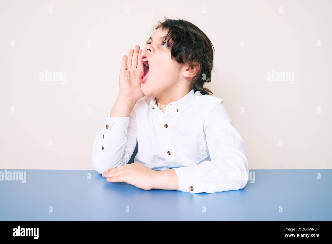 Cute hispanic child wearing casual clothes sitting on the table ...