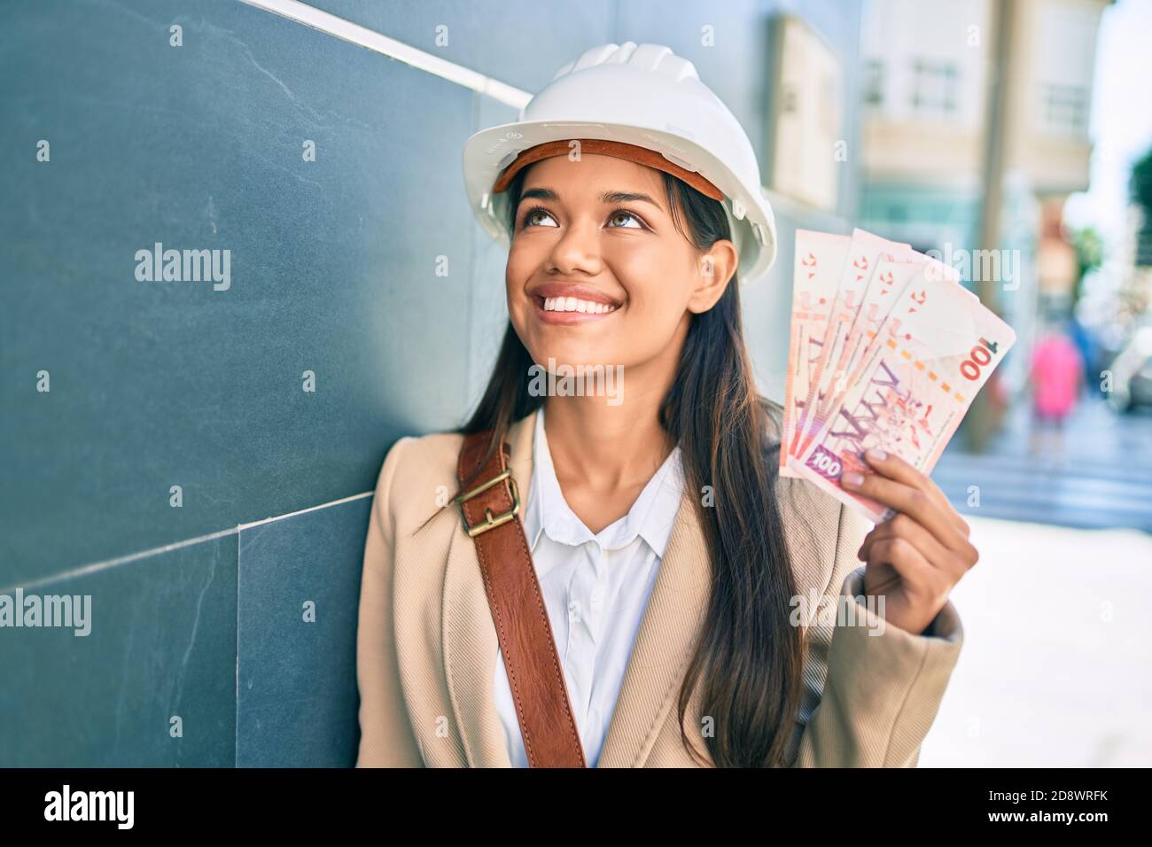 Young latin architect girl smiling happy holding hong kong dollars ...