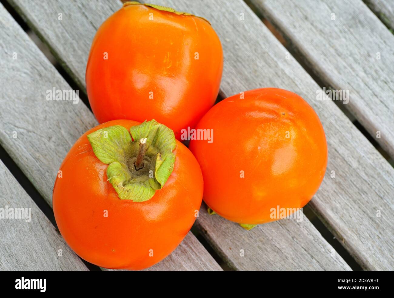 Three Hachiya orange persimmon kaki fruits Stock Photo - Alamy