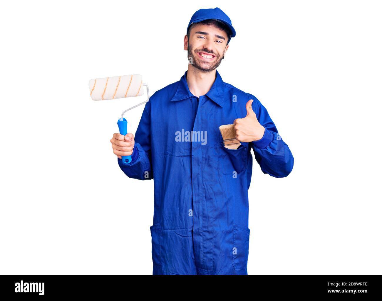 Young hispanic man wearing painter uniform holding roller smiling happy ...