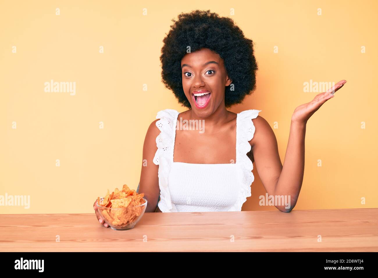 Young african american woman holding nachos potato chips celebrating ...