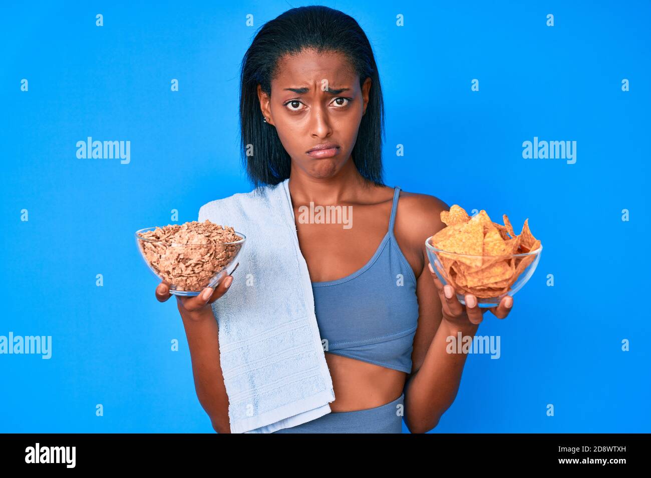 Young african american woman wearing sportswear holding nachos and ...