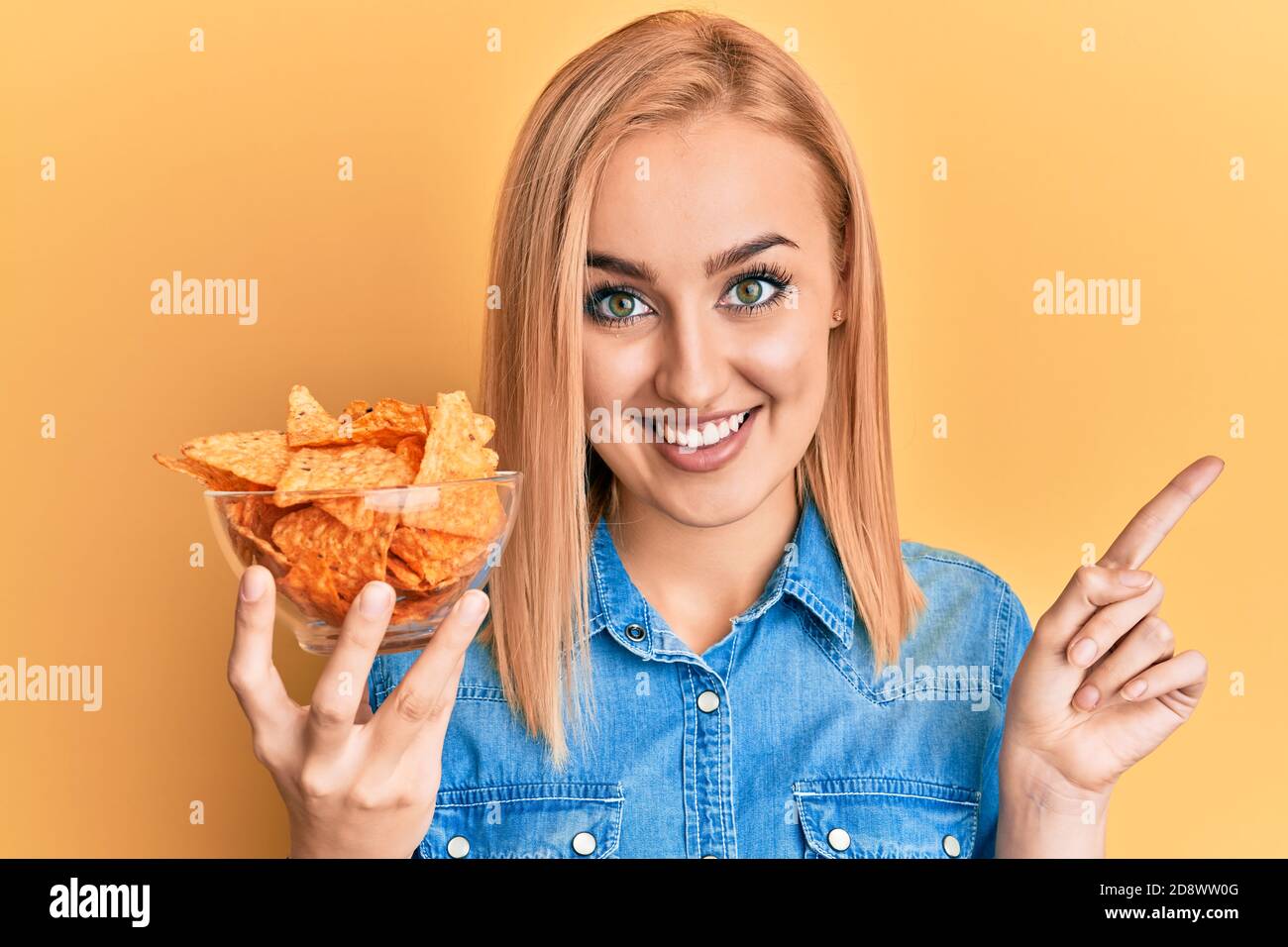 Beautiful caucasian woman holding nachos potato chips smiling happy ...