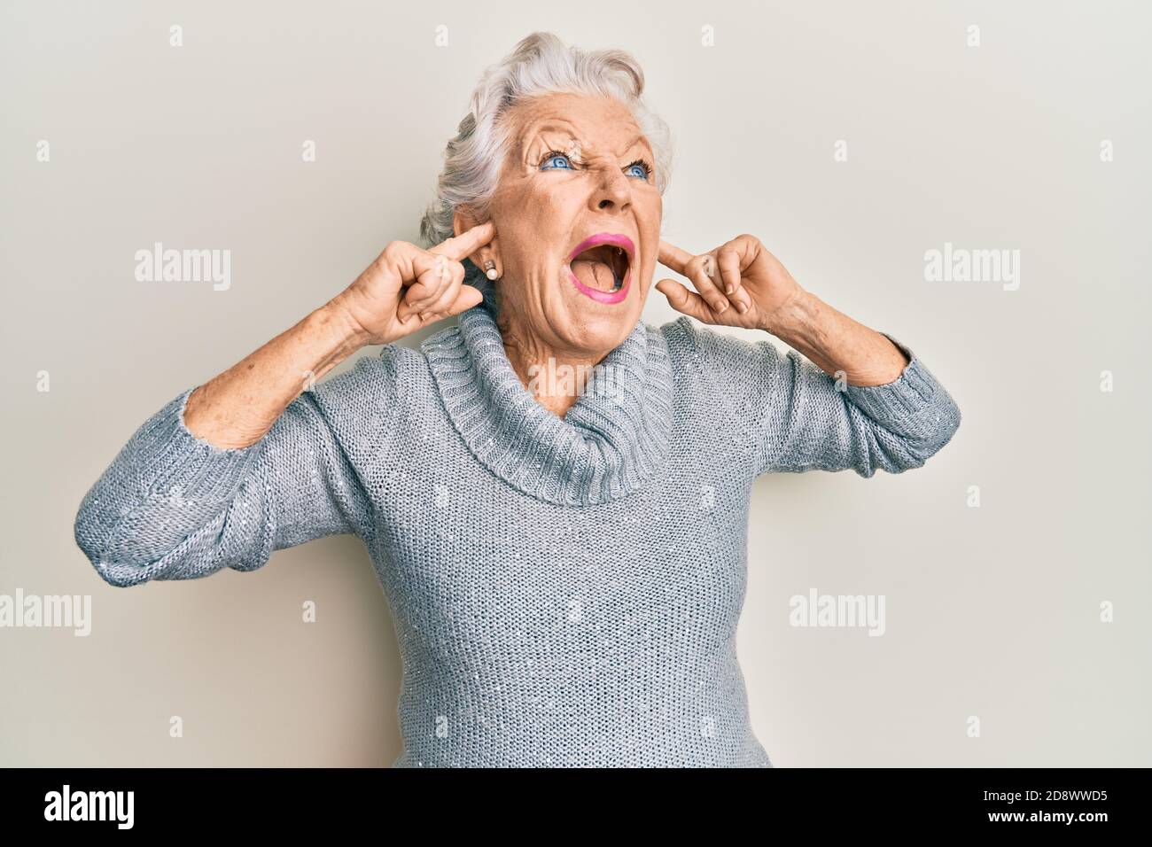 Senior grey-haired woman covering ears with finger angry and mad ...
