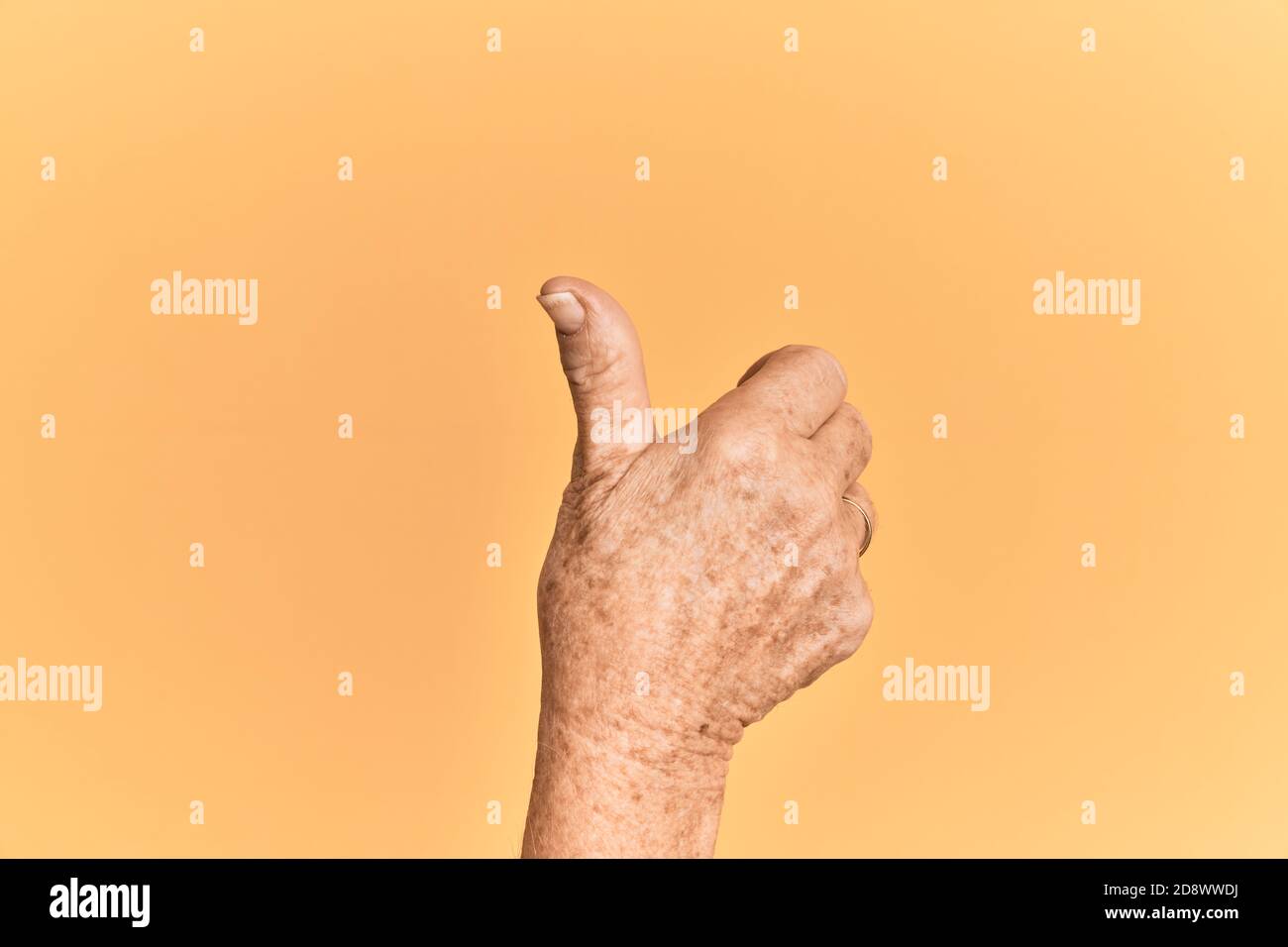 Senior caucasian hand over yellow isolated background holding invisible ...