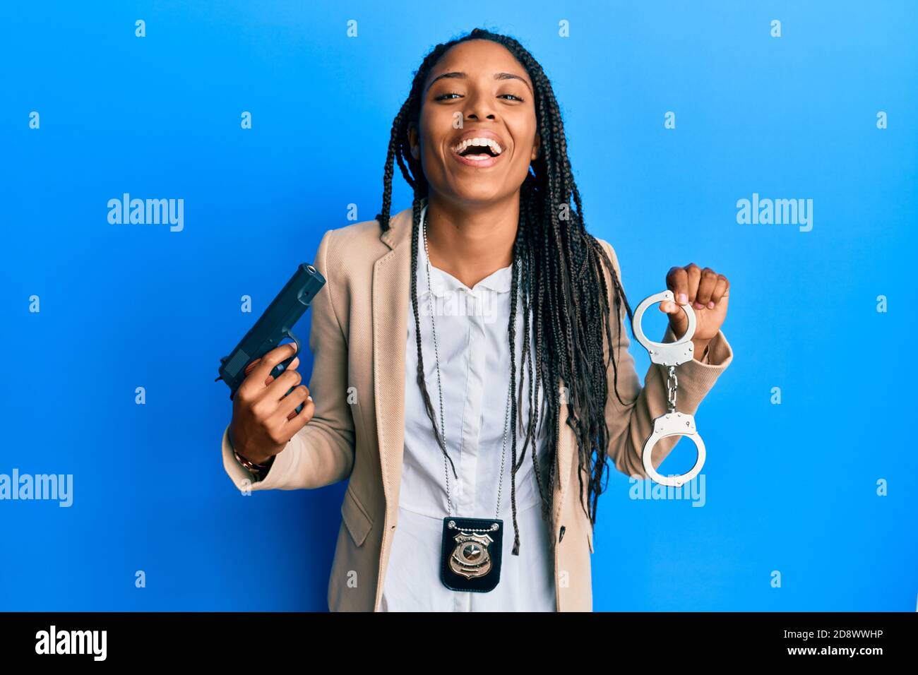 African american police woman holding gun and handcuffs smiling and ...