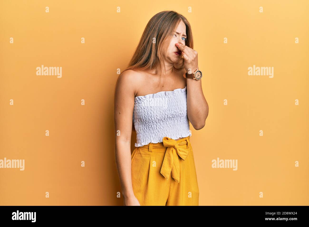 Beautiful young blonde woman wearing casual summer clothes smelling ...