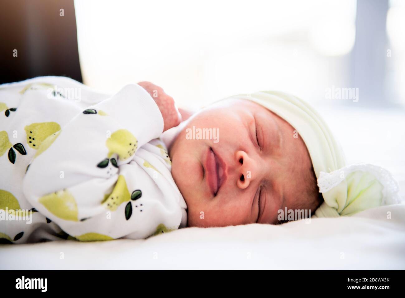 A newborn baby laying down sleeping on a soft white background. Use the ...
