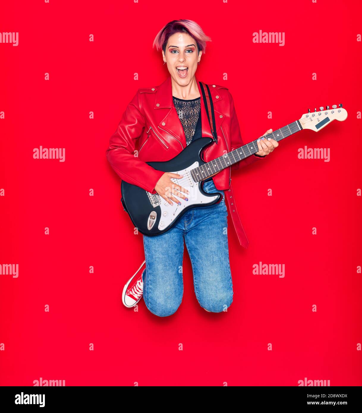 Young beautiful guitarist woman with pink short hair playing electric ...