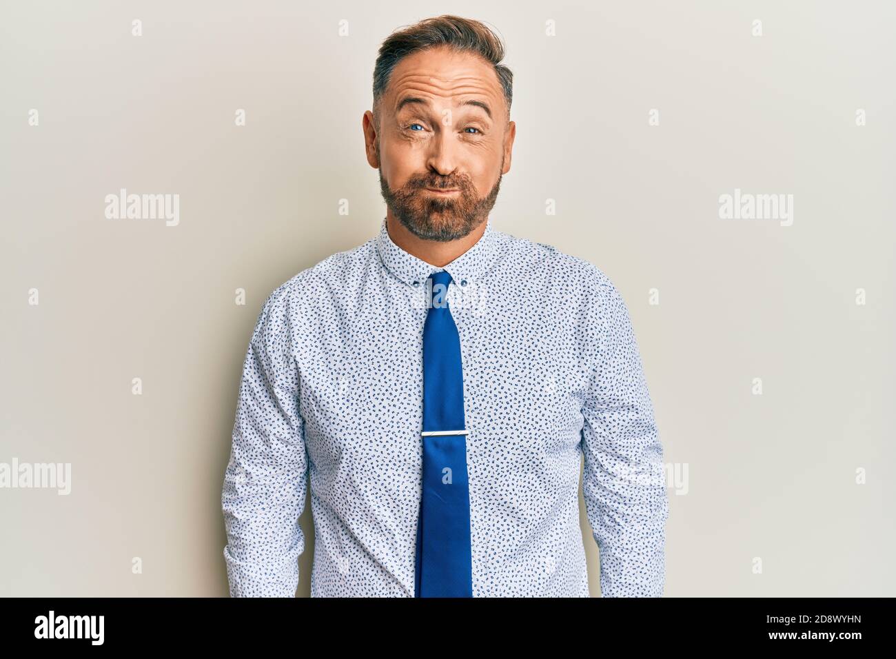 Handsome middle age man wearing business shirt and tie puffing cheeks ...