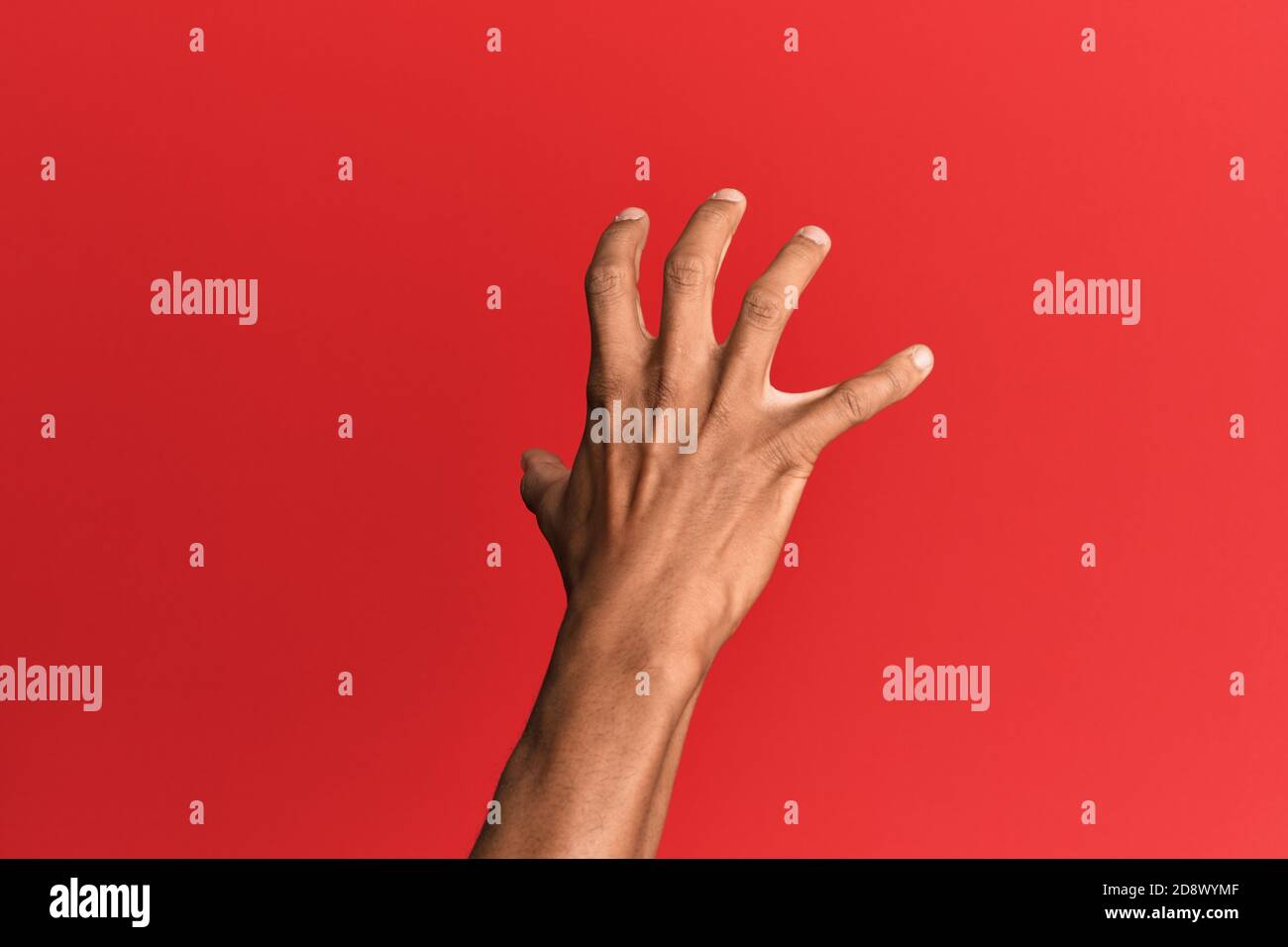 Hand of hispanic man over red isolated background grasping aggressive ...