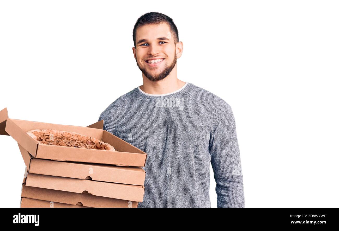 Young handsome man holding delivery italian pizza boxes looking ...