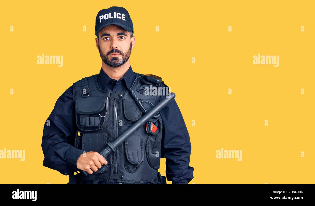 Young hispanic man wearing police uniform holding baton thinking ...
