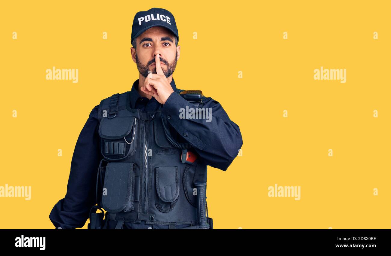 Young hispanic man wearing police uniform asking to be quiet with ...