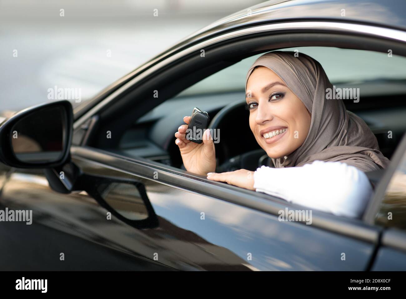 Young muslim lady showing auto keys, sitting on driver's seat Stock ...