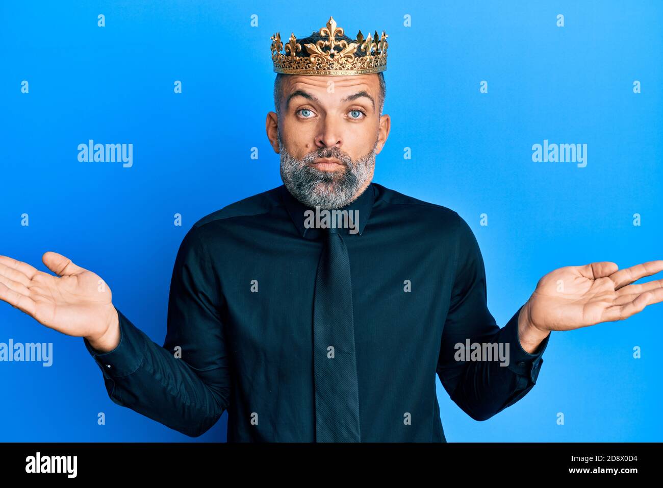 Middle age handsome business man wearing king crown clueless and ...