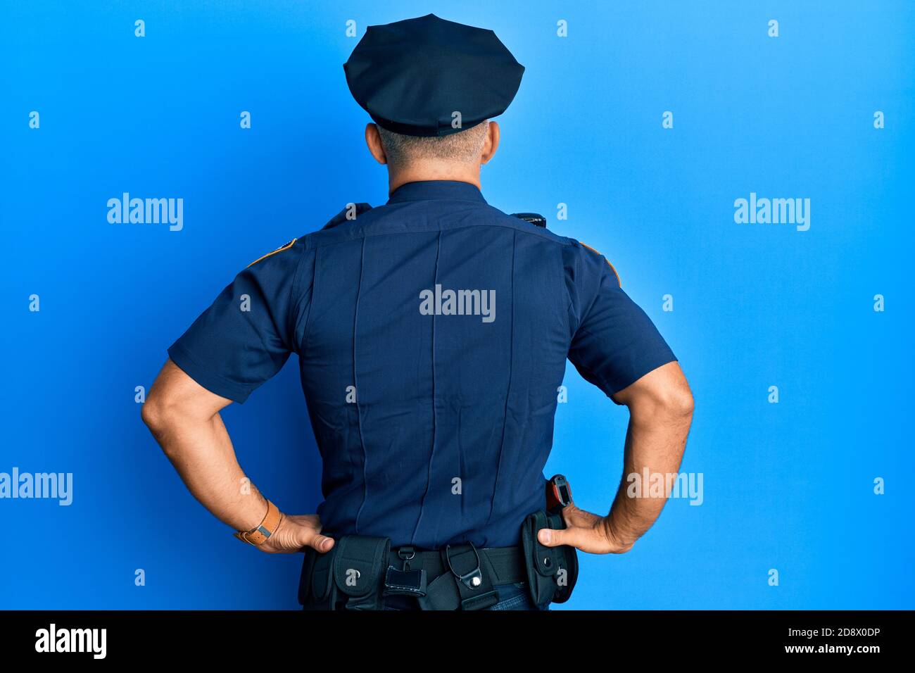 Middle age handsome man wearing police uniform standing backwards ...