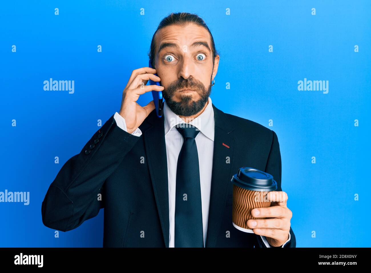 Attractive business man with long hair and beard using smartphone and ...