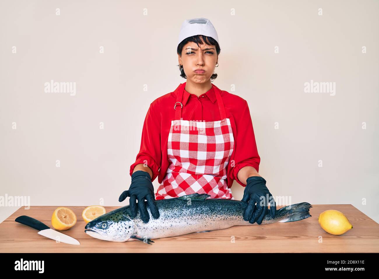 Beautiful brunettte woman fishmonger cooking fresh raw salmon puffing ...