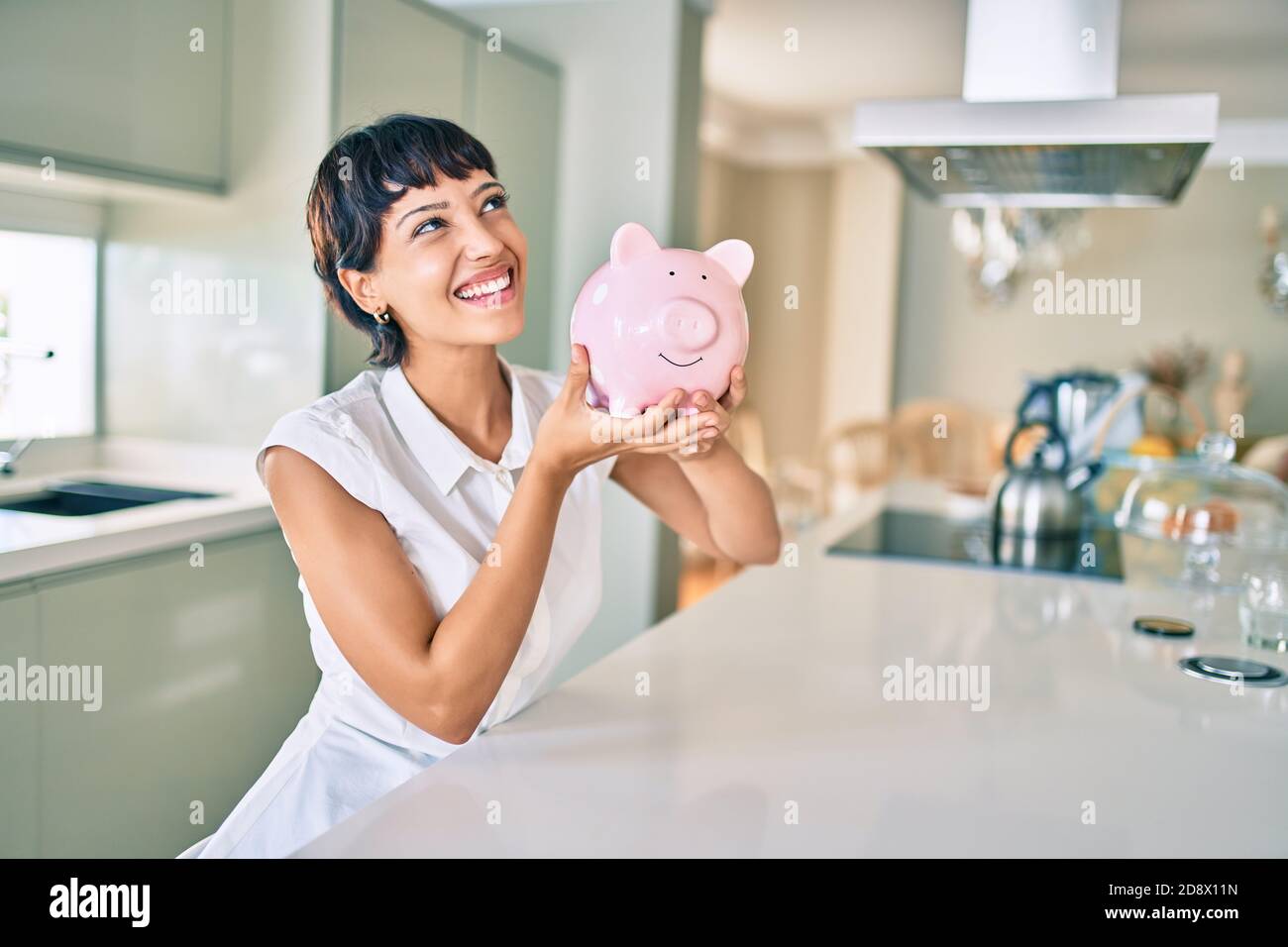 Young brunette woman smiling happy showing proud piggy bank with ...