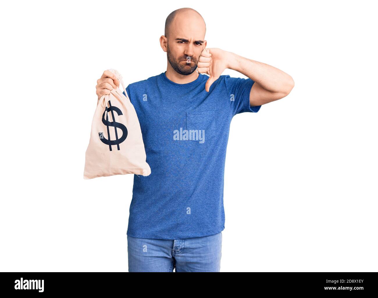 Young handsome man holding money bag with dollar symbol with angry face ...