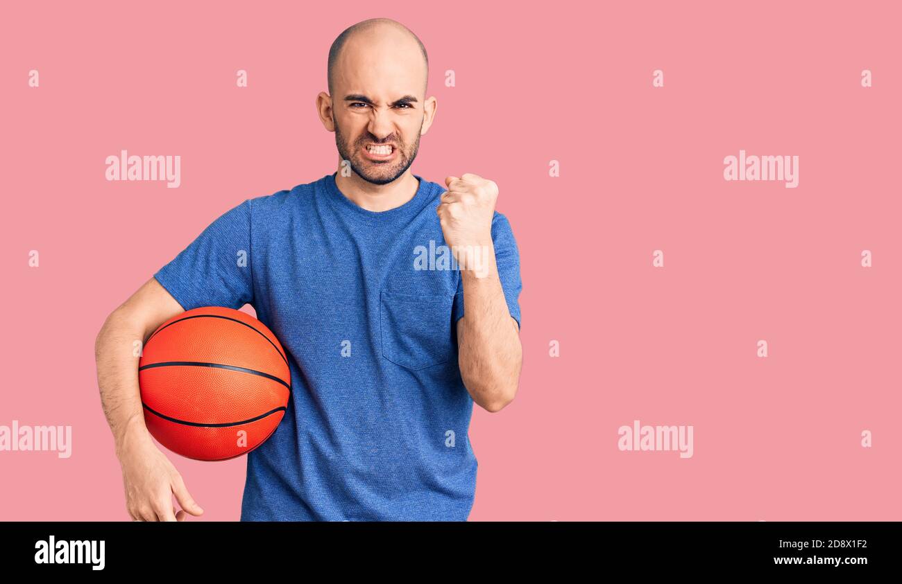 Young handsome man holding basketball ball annoyed and frustrated ...