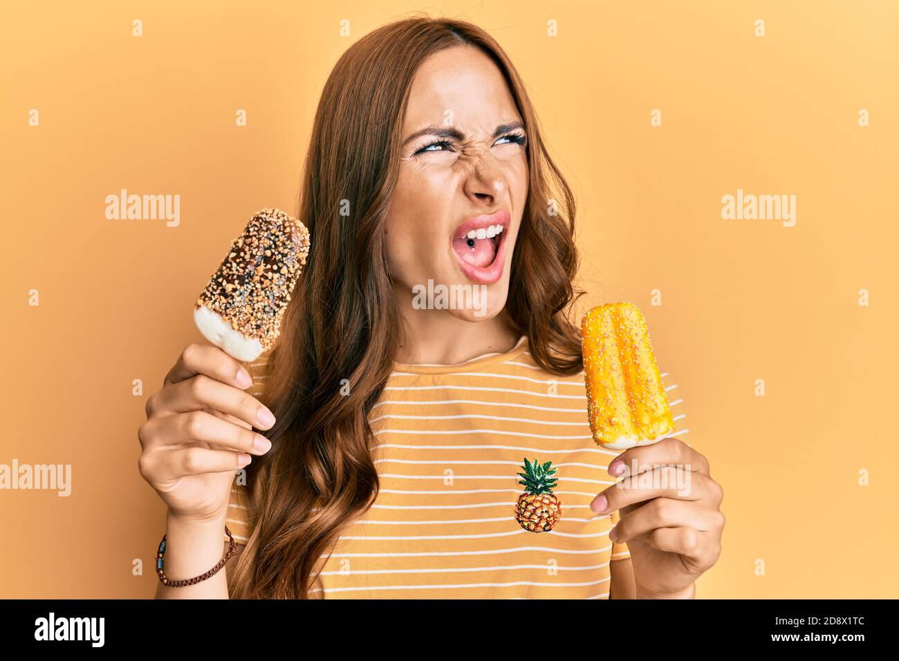 Young brunette woman wearing summer style holding ice cream angry and ...