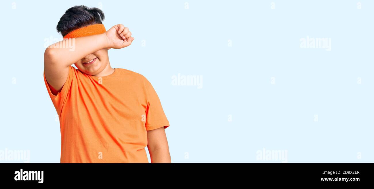 Little boy kid wearing sportswear covering eyes with arm smiling ...