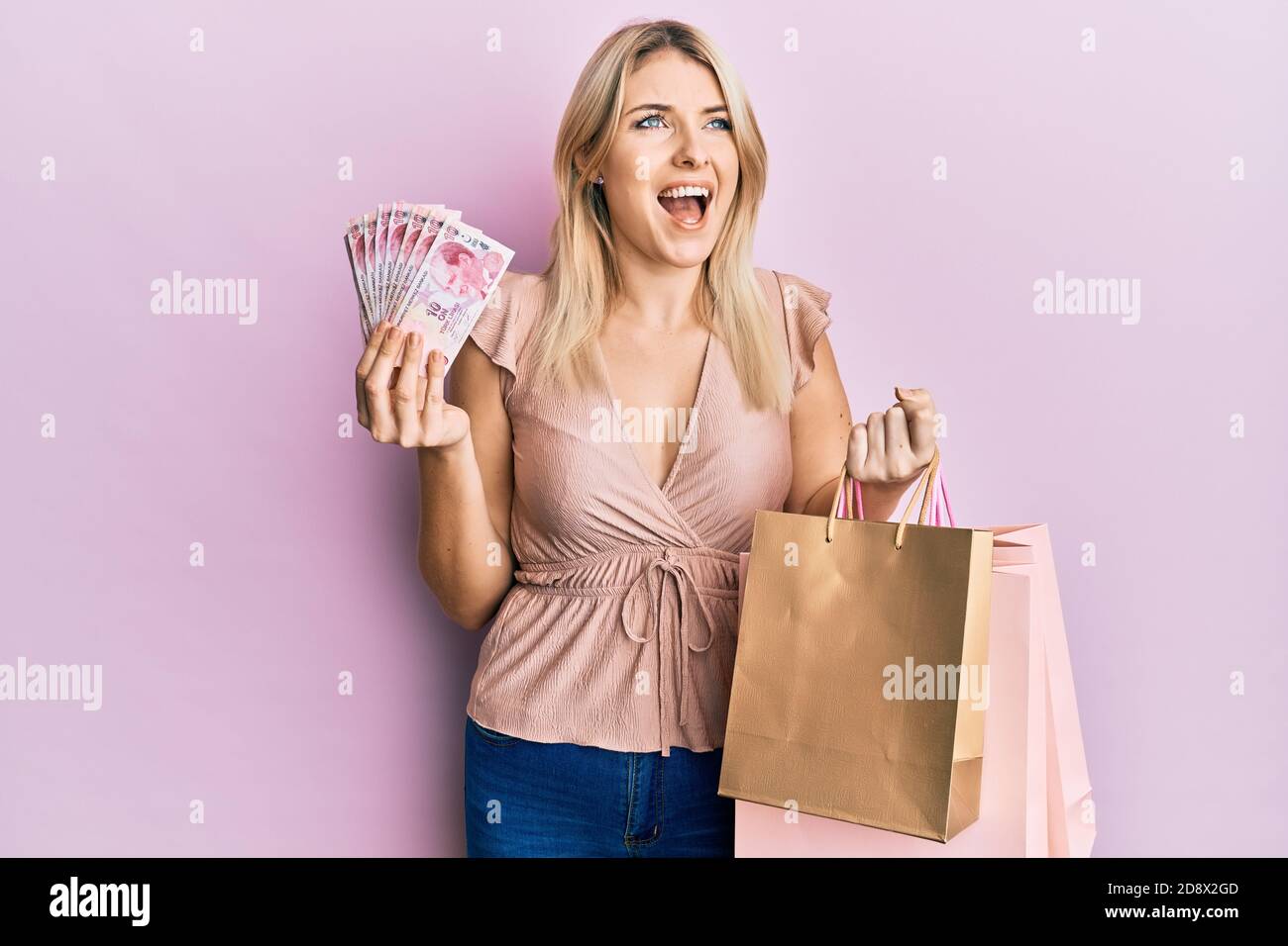 Young caucasian woman holding turkish lira banknotes and shopping bags ...