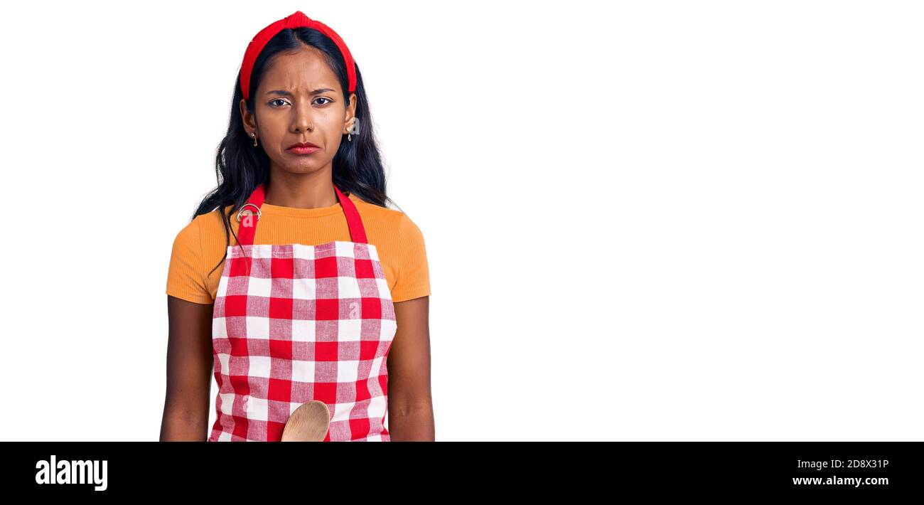 Young indian girl wearing professional baker apron depressed and worry ...