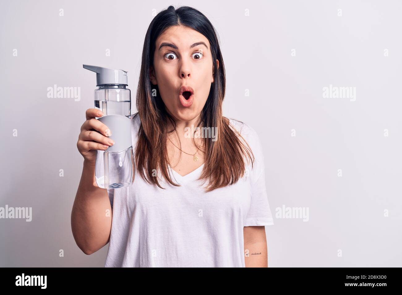 Young beautiful brunette woman drinking bottle of water over isolated ...