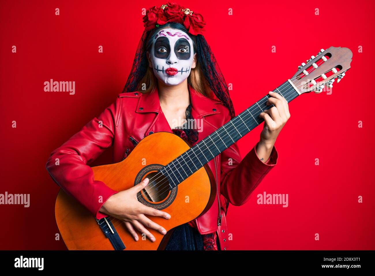Woman wearing day of the dead costume playing classical guitar puffing ...