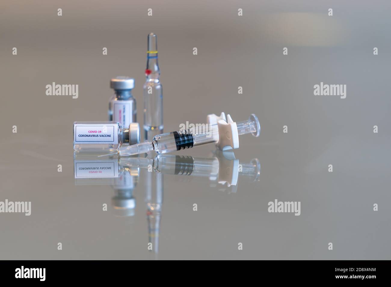 A sideways mini vial of COVID-19 Coronvavirus vaccine with a syringe on ...