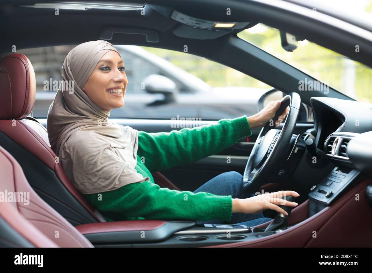 Smiling muslim woman driving her new car in city Stock Photo - Alamy