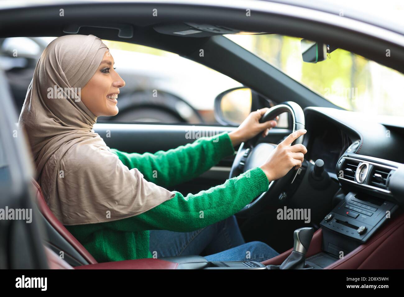 Smiling muslim woman test driving new car in urban city Stock Photo - Alamy