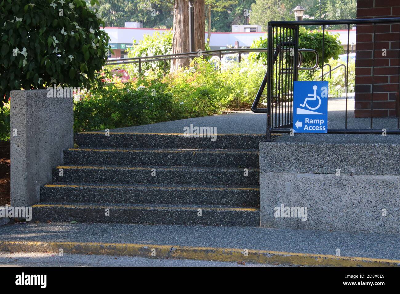 A blue ramp access sign pointing to a ramp off to the left with stairs ...