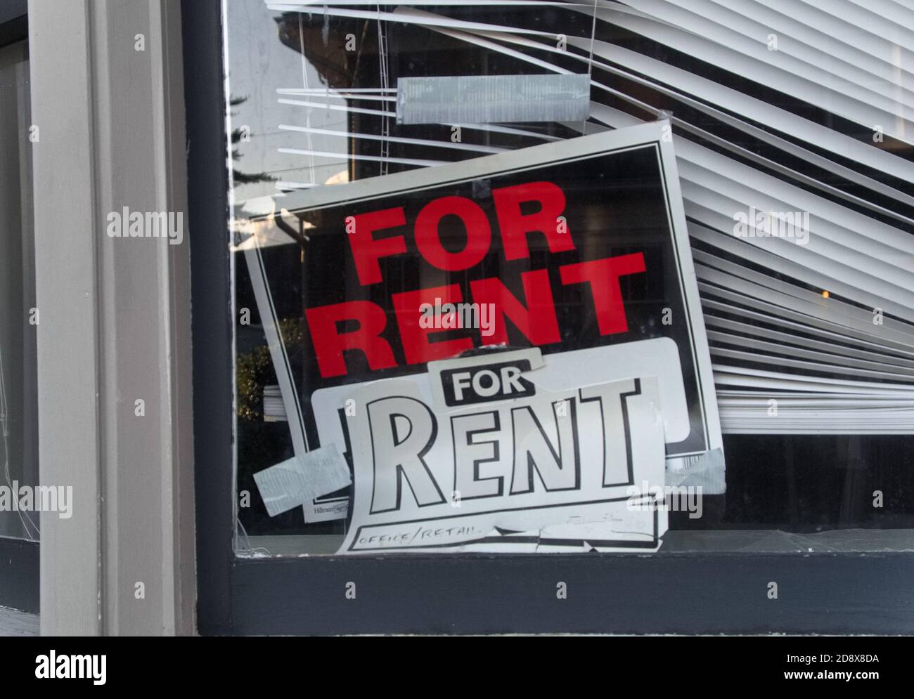 A crooked "For Rent" sign displayed in a window with crooked, broken ...